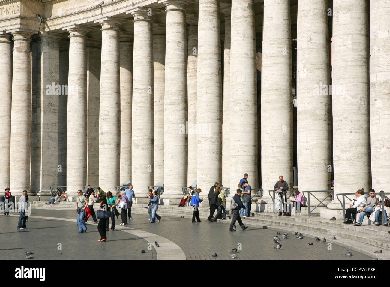 Tourists rest from sightseeing beneath the huge white stone columns of ...