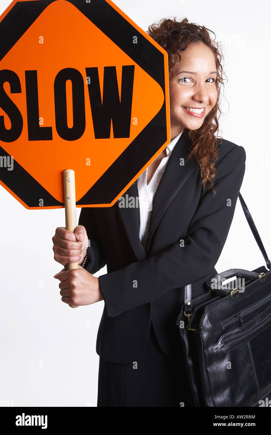young businesswoman peeking behind SLOW sign Stock Photo - Alamy