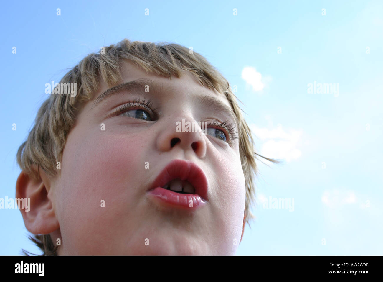 seven year old boy expressing himself outdoors with blue sky background ...