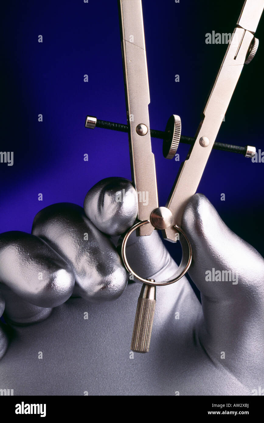 Silver hand holding drafting compass Stock Photo - Alamy