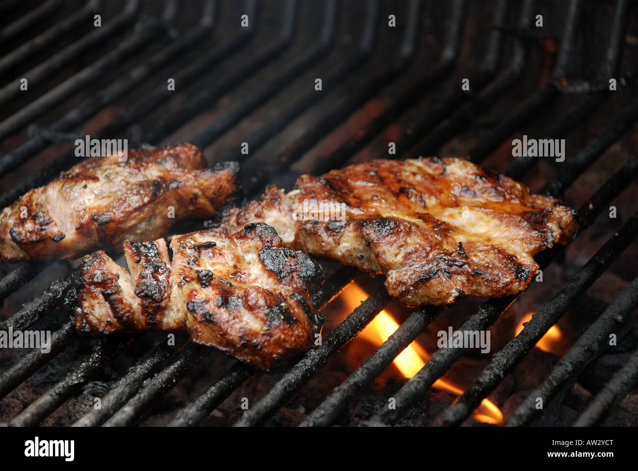 Meat cooking on barbecue grill with flames Stock Photo - Alamy