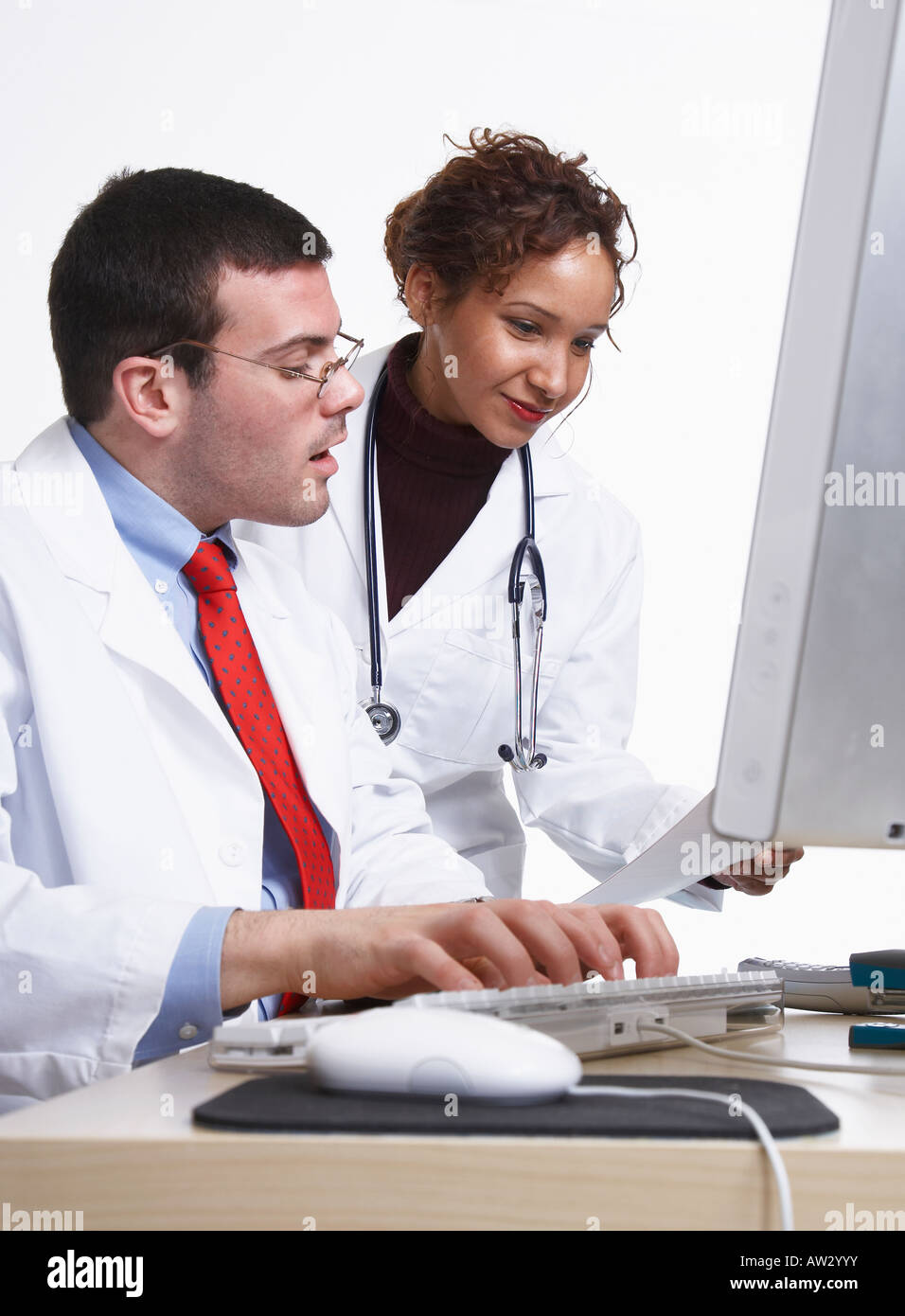 two medical doctors looking at chart at computer desk Stock Photo - Alamy