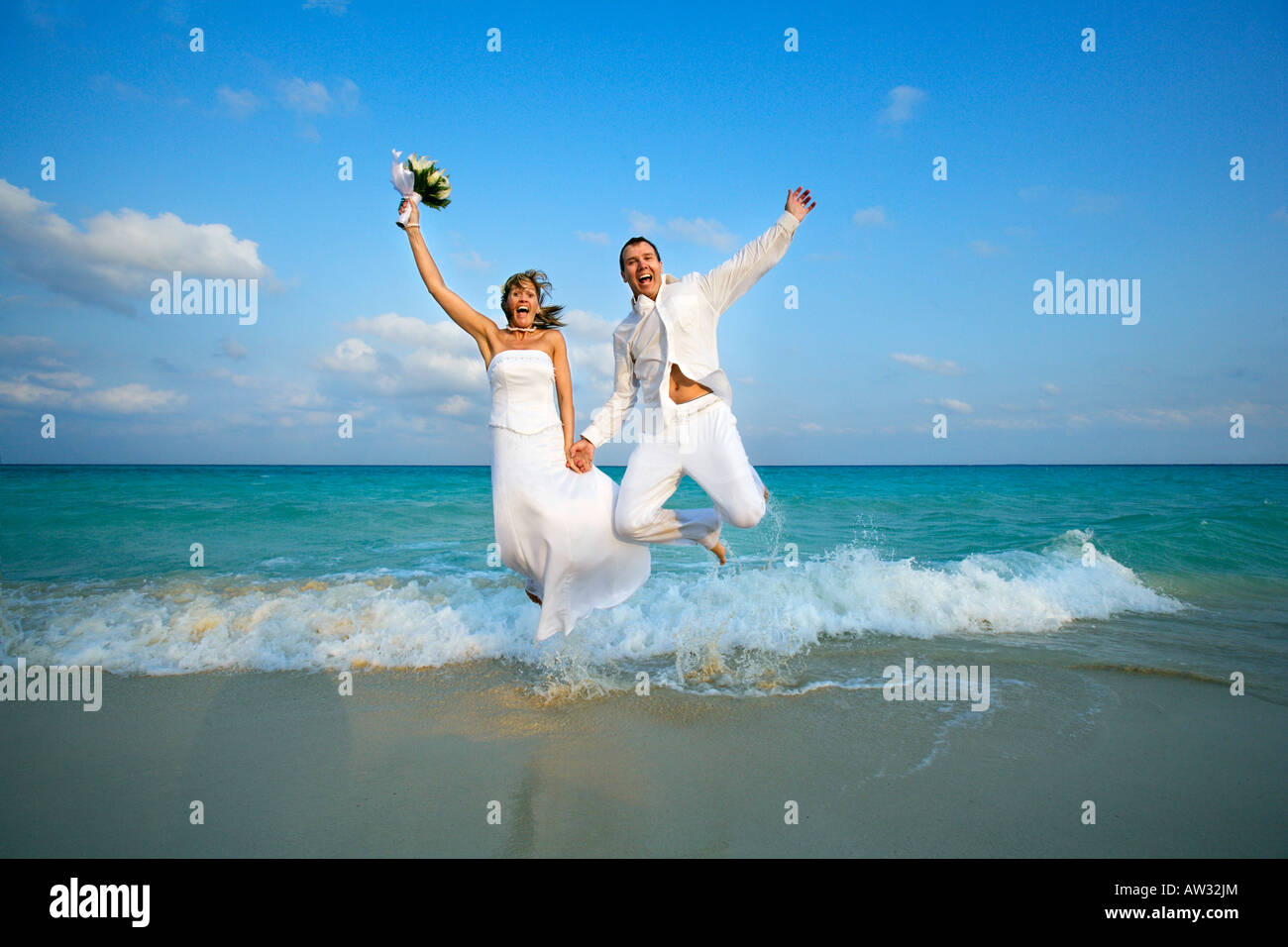 Married couple jumping on the beach Stock Photo - Alamy