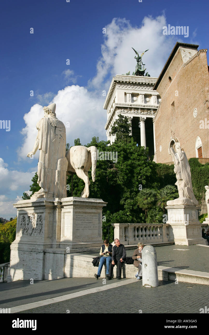 Tourists rest beneath huge Roman stone statues at the entrance to ...