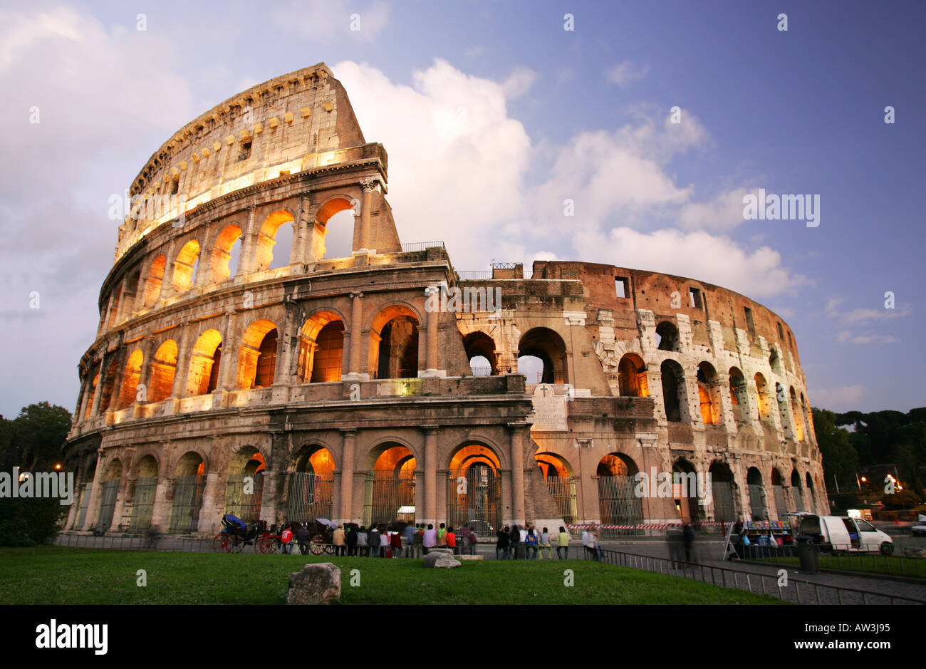 Tourists gather to watch the Colosseum in Rome light up at dusk ...