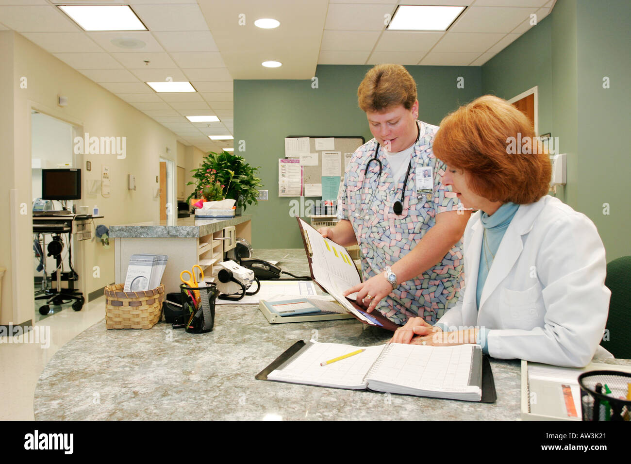 2 nurses discuss a patient's chart at the nurse's station Stock Photo ...