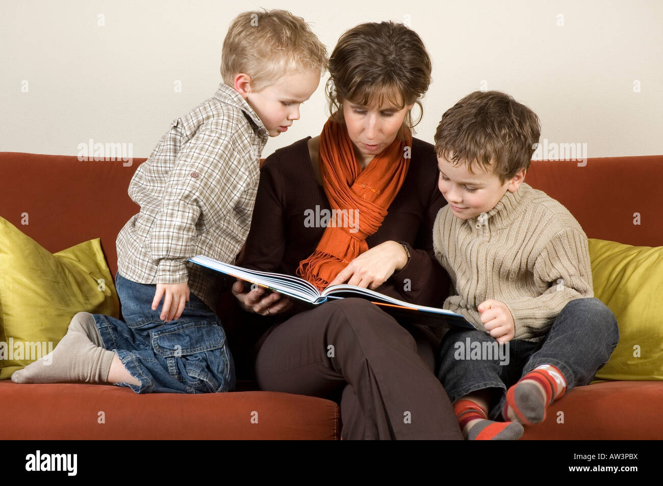Mother and her two sons reading a book on a couch Stock Photo - Alamy