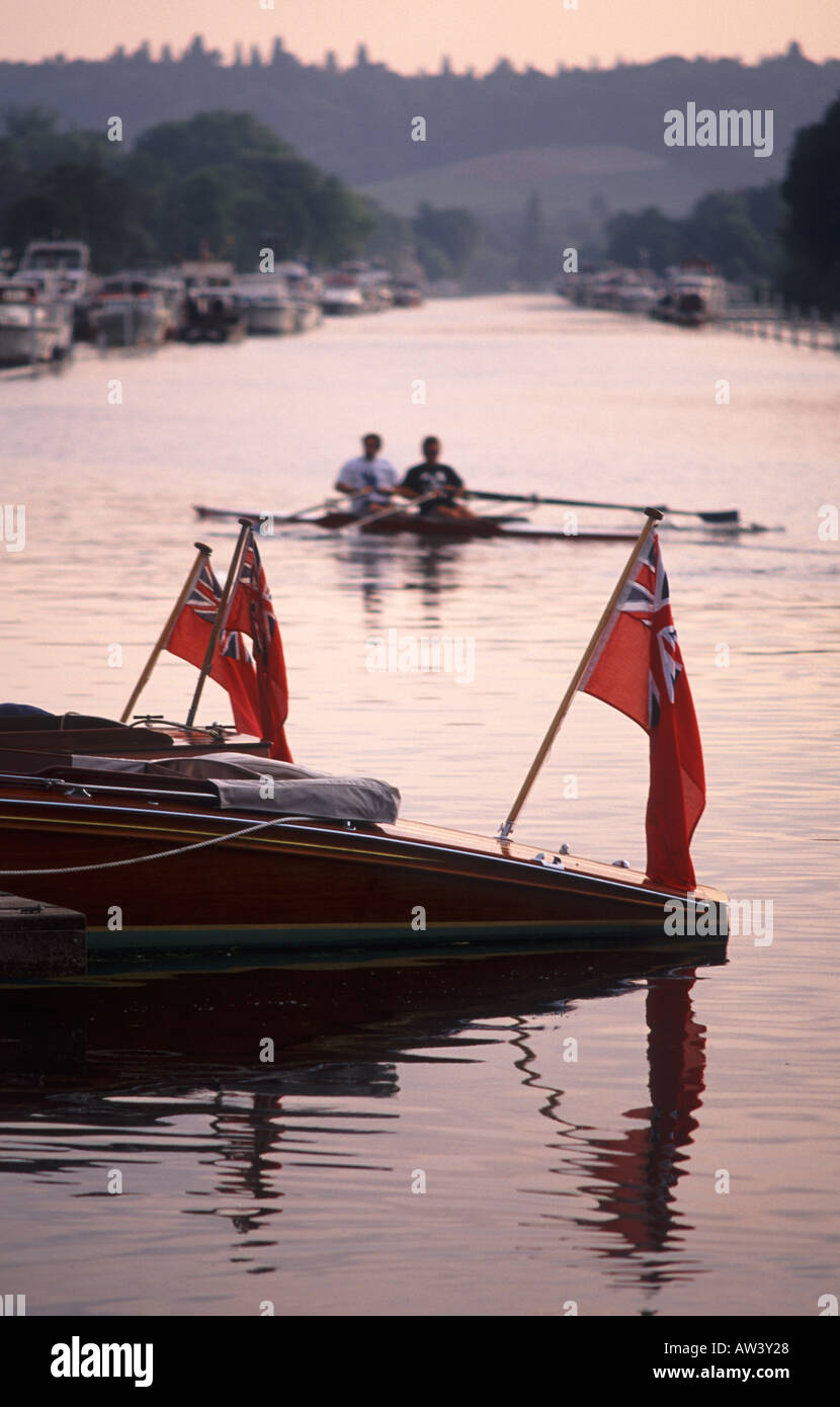 Red ensigns on slipper stern launches at dawn on River Thames; two men ...