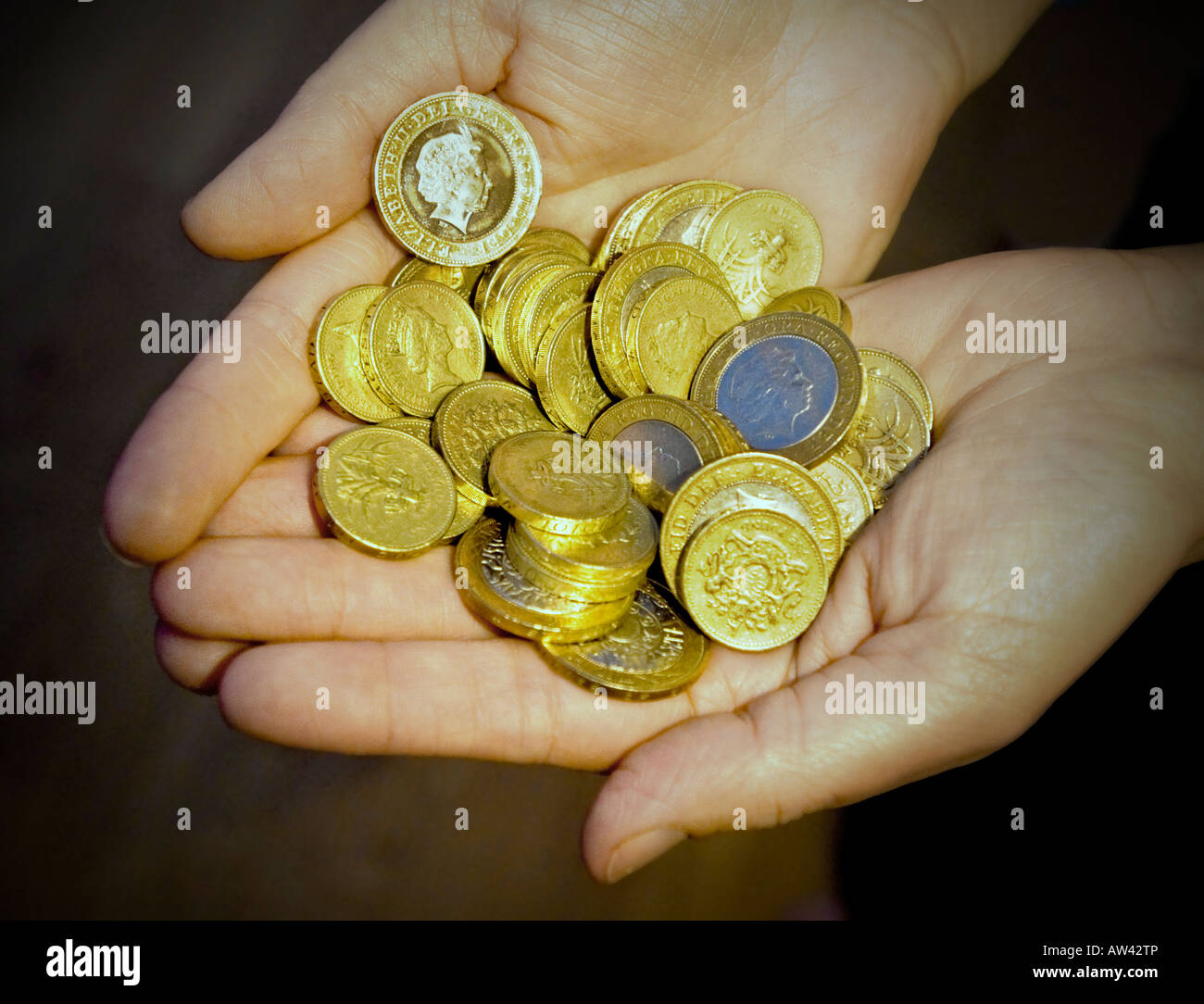 English one pound coins and two pound coins in cupped hands Stock Photo ...