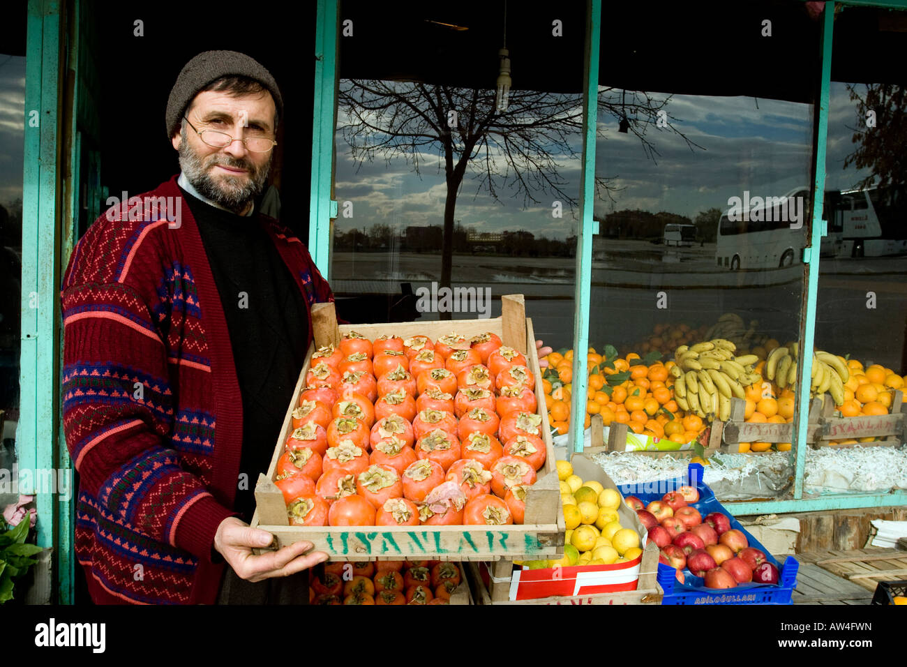 A Fruit shop owner holding a tray of fresh produce outside his shop in ...