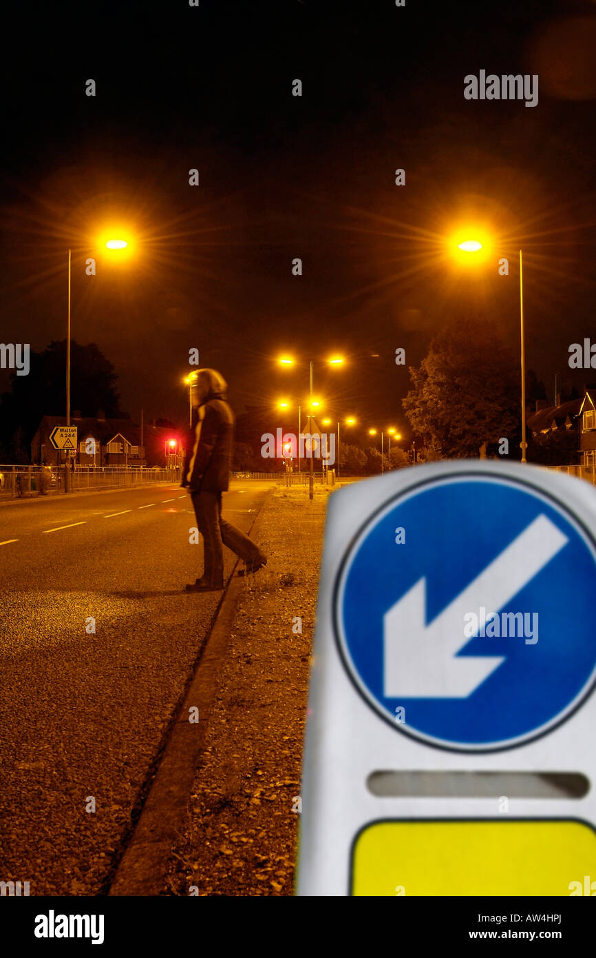 Pedestrian crossing a well-lit road at night Stock Photo - Alamy