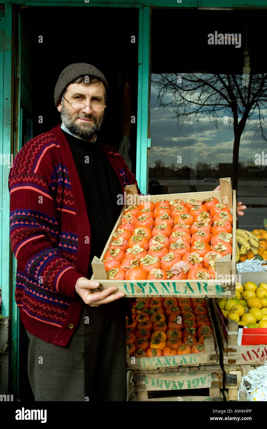 A Fruit shop owner holding a tray of fresh produce outside his shop in ...