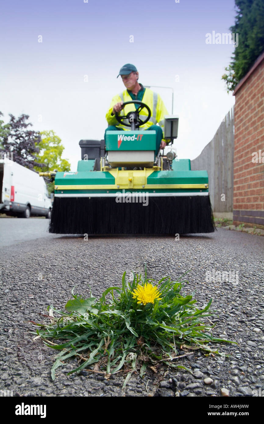 Council worker spraying weeds on a pavement with a ride-on sprayer ...