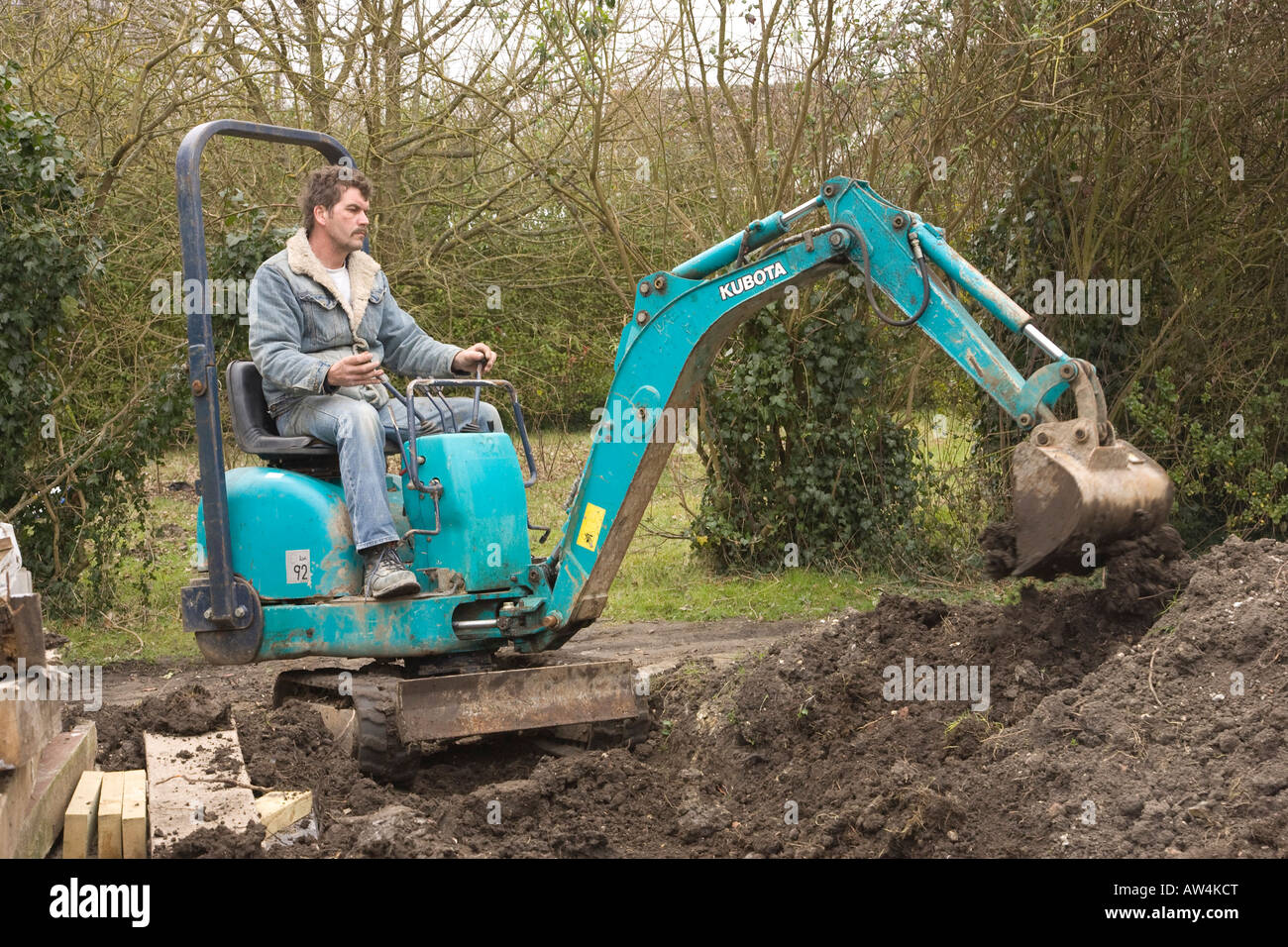 a man driving a mini digger / excavator Stock Photo - Alamy