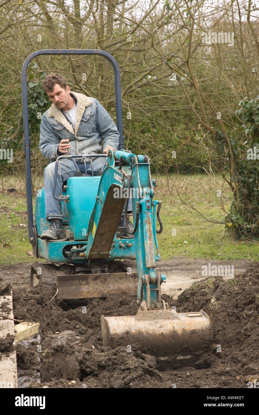 a man driving a mini digger / excavator Stock Photo - Alamy