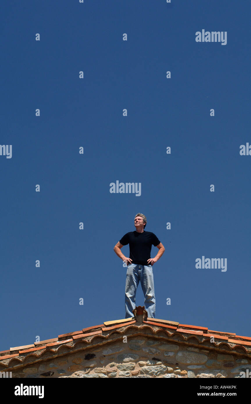 Man standing on roof of building with blue sky Stock Photo - Alamy