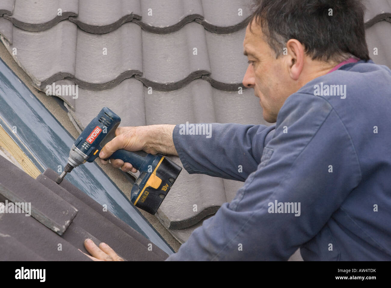 a builder fitting tiles to a roof of a new home Stock Photo - Alamy