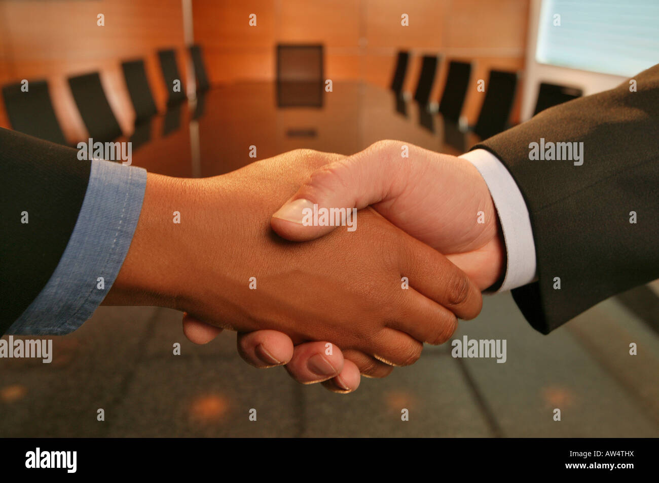 Two business men shake hands over a corporate board room table Stock ...