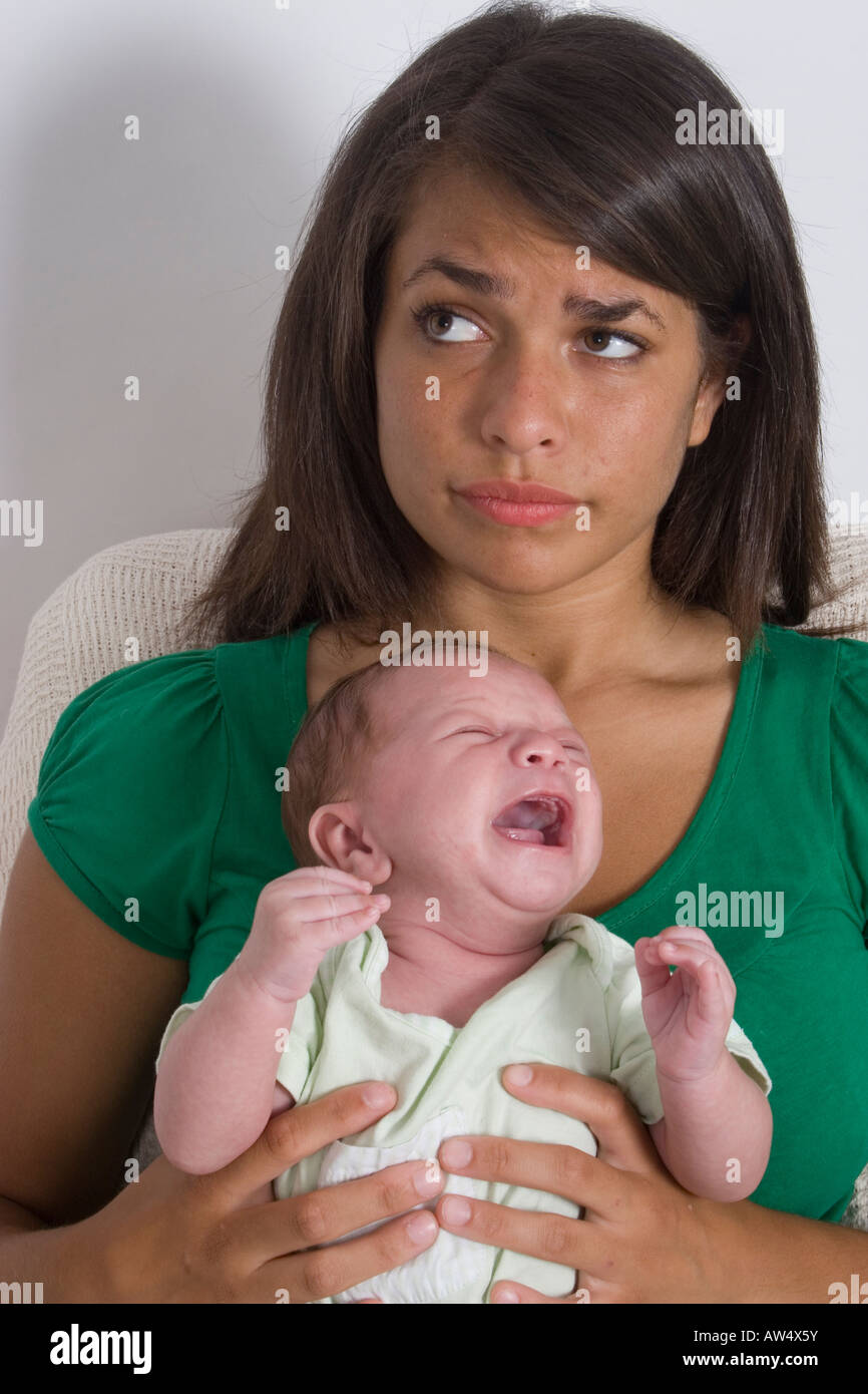 distraught young mother or childminder holding crying baby Stock Photo ...