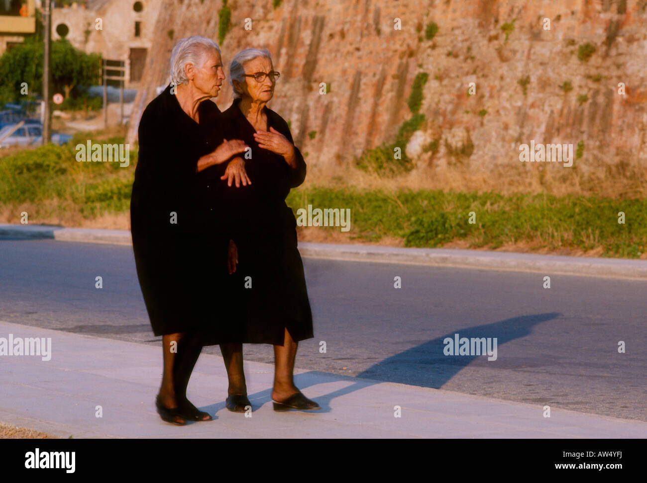 Two elderly Greek women dressed in black taking an evening stroll ...