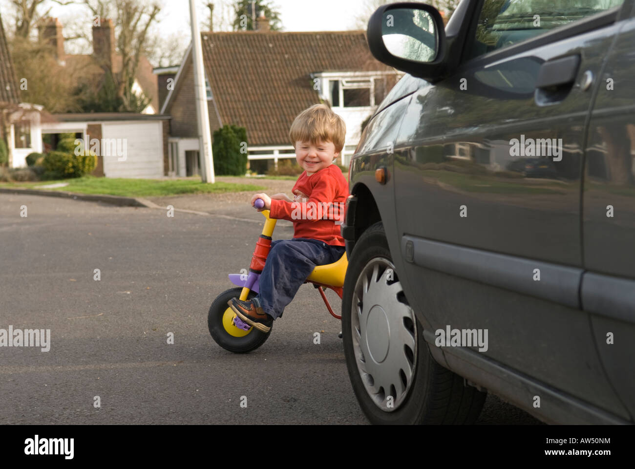 two year old boy on bike in danger on road pulling out from behind a ...