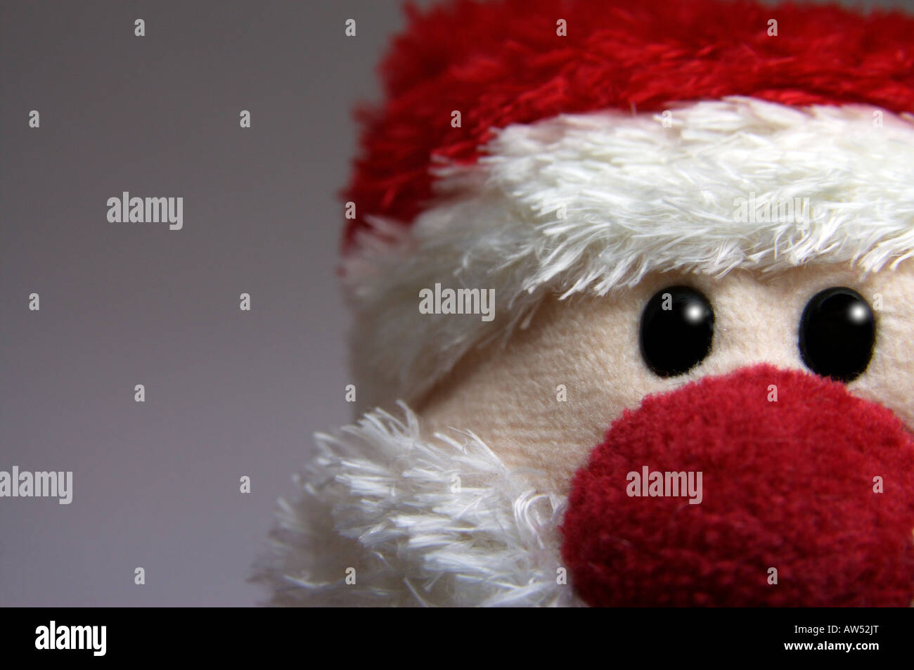A close-up of a soft-toy Father Christmas against a grey background ...