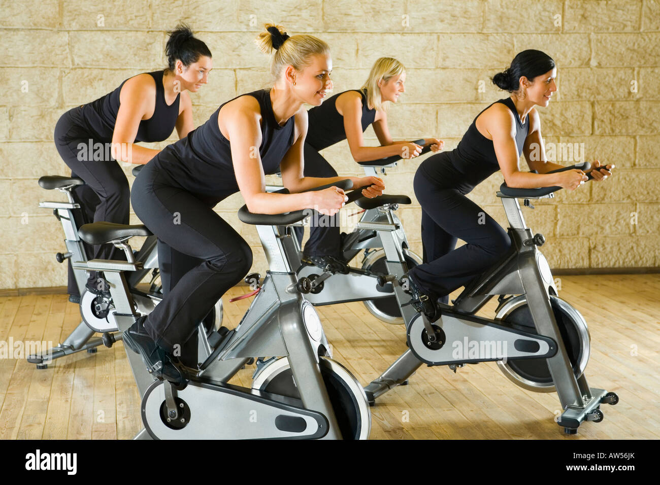 The group of women training on exercise bikes at the gym Side view ...