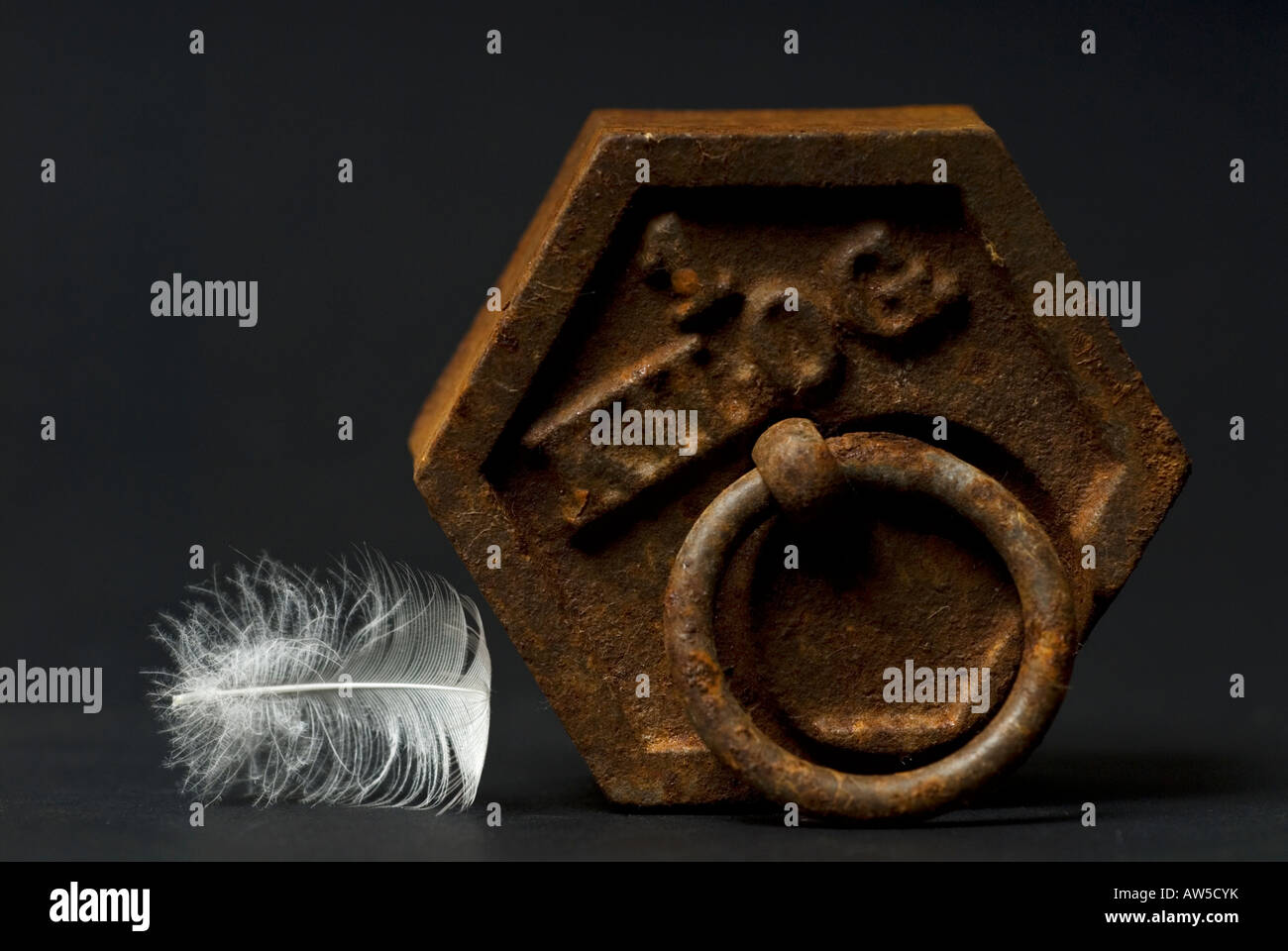 Stock photo of a white feather next to a rusty 1 kilo weight Stock ...