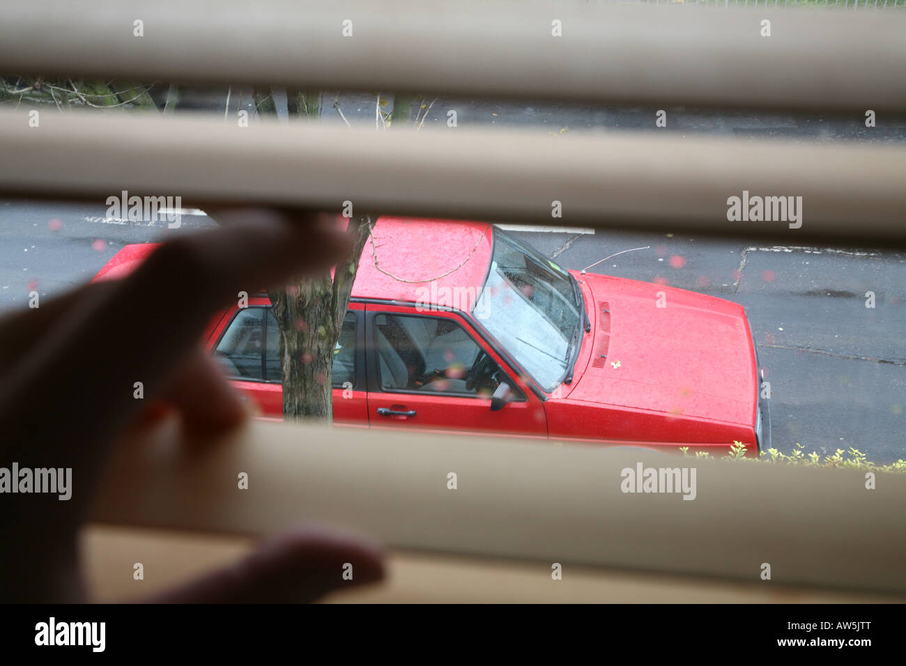 Peering through the blinds watching car and street below Stock Photo ...