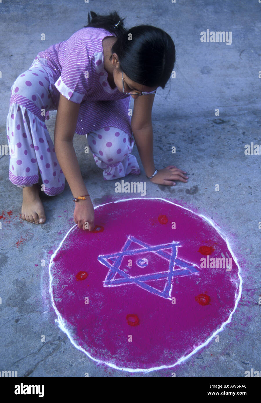 A Hindu girl drawing a rangoli outside her house on the occasion of ...