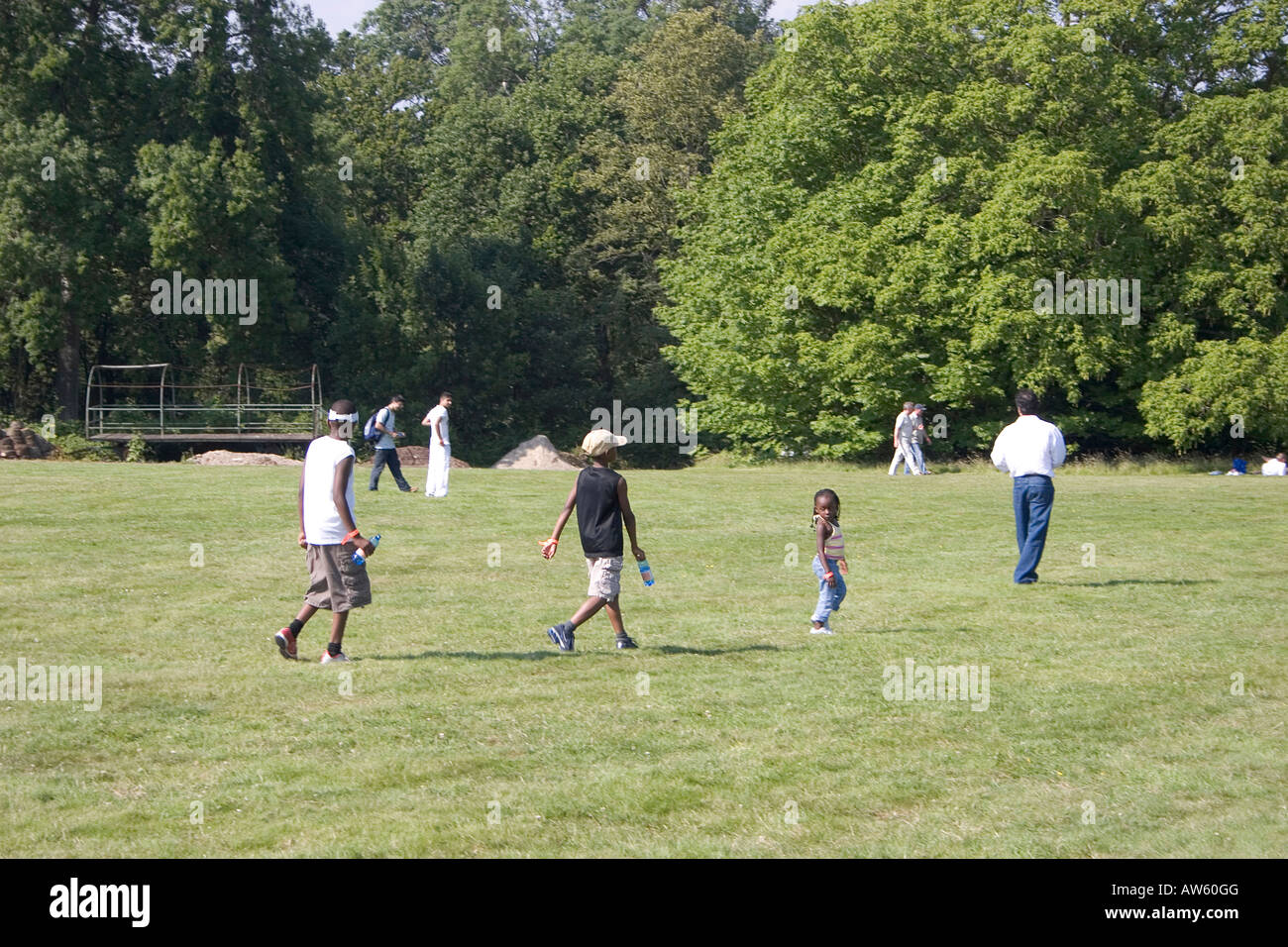 Three children of colour following their father through a field in the ...