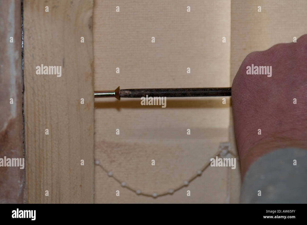 Screwing batten to wall Stock Photo - Alamy