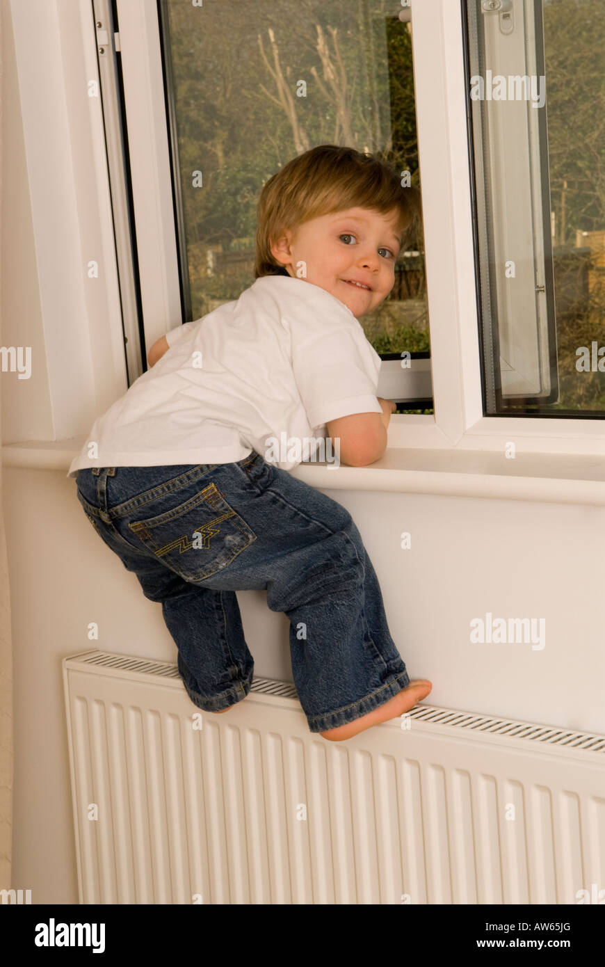 two year old boy in danger climbing up to an open window standing on a ...