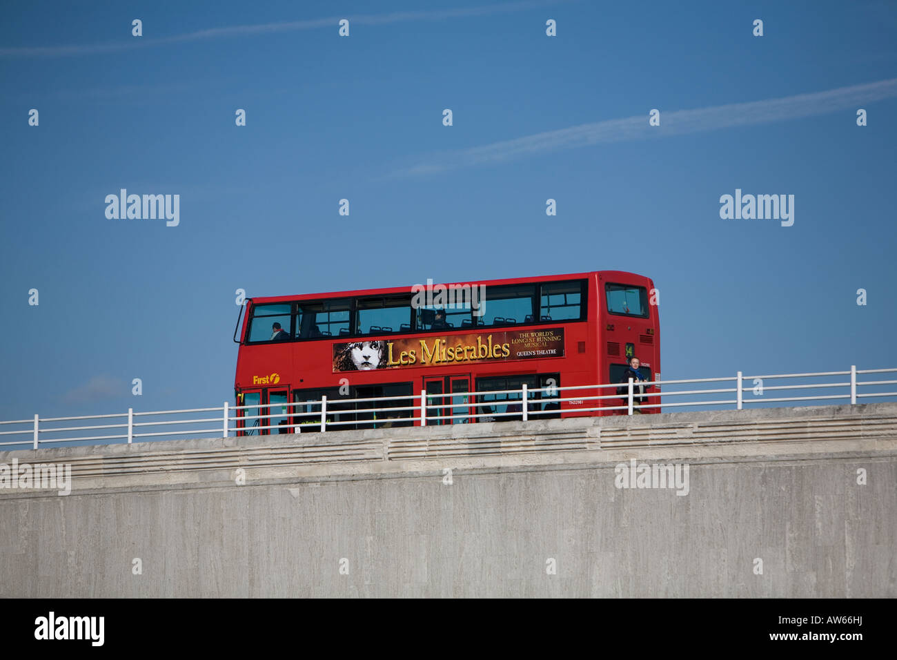 A red London double decker bus crosses London Bridge over the River ...