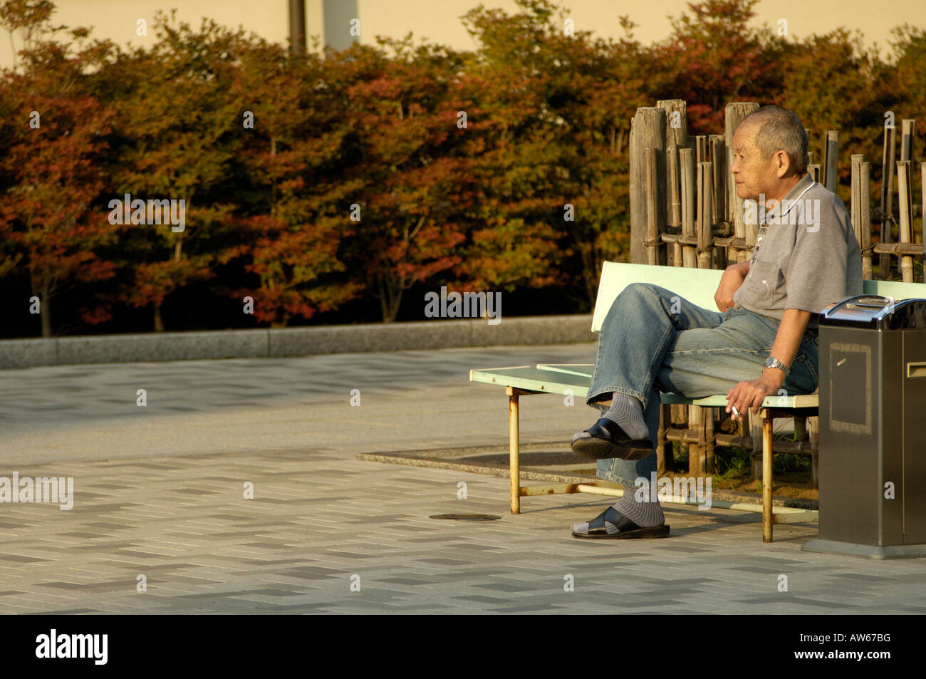 Japanese man sitting on bench in evening sunshine at the Sengaku-ji ...