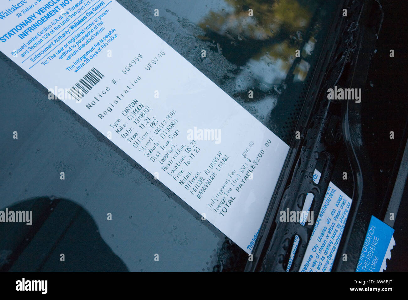 A parking ticket on a car wind shield under the wind shield wiper ...