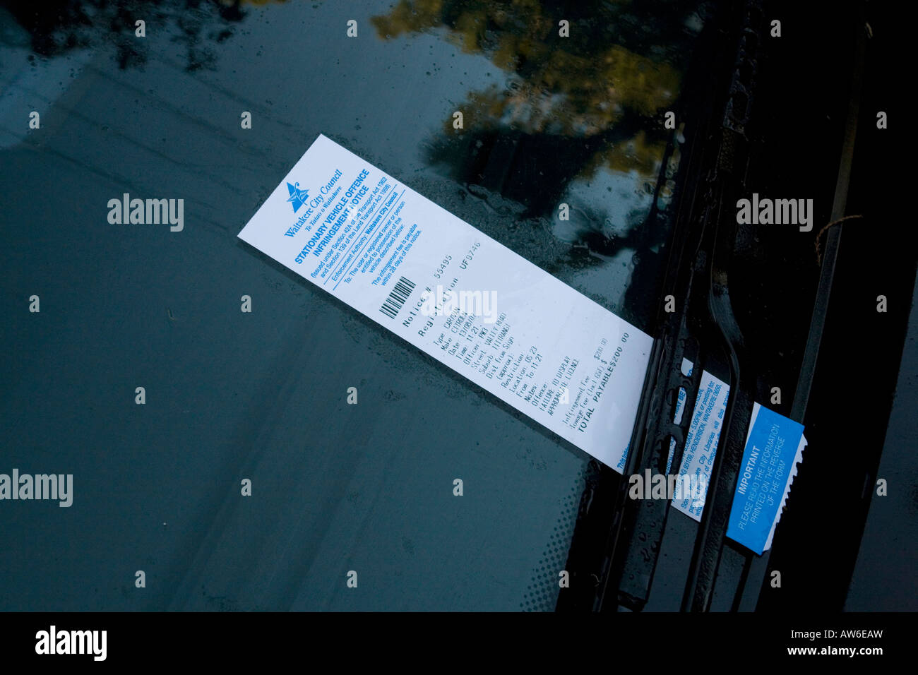 A parking ticket on a car wind shield under the wind shield wiper ...