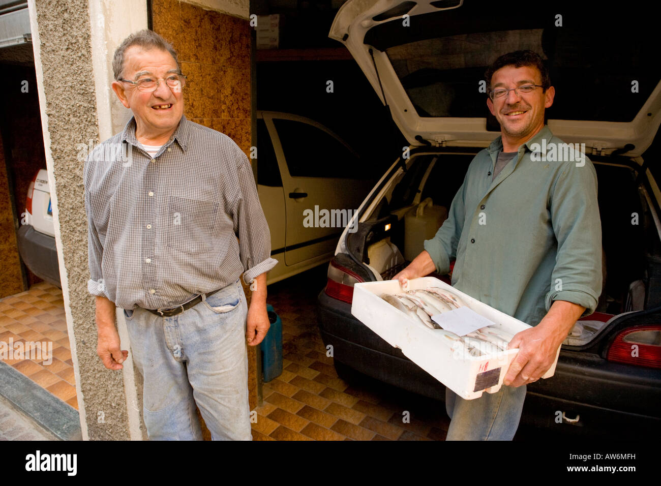 Two fishermen carry fish to market Stock Photo - Alamy