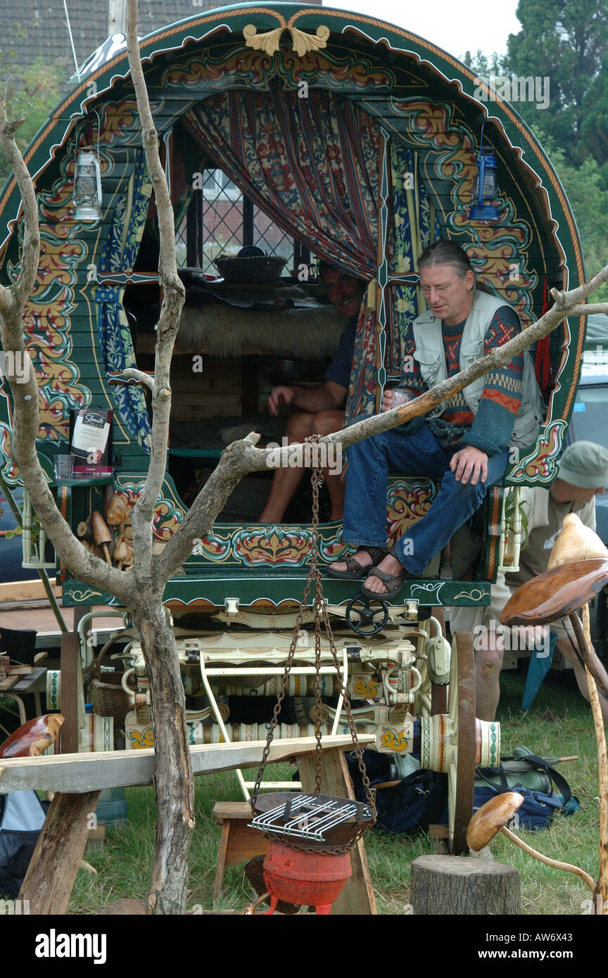 man sitting on the steps of a bow top gypsy caravan, at the big green ...