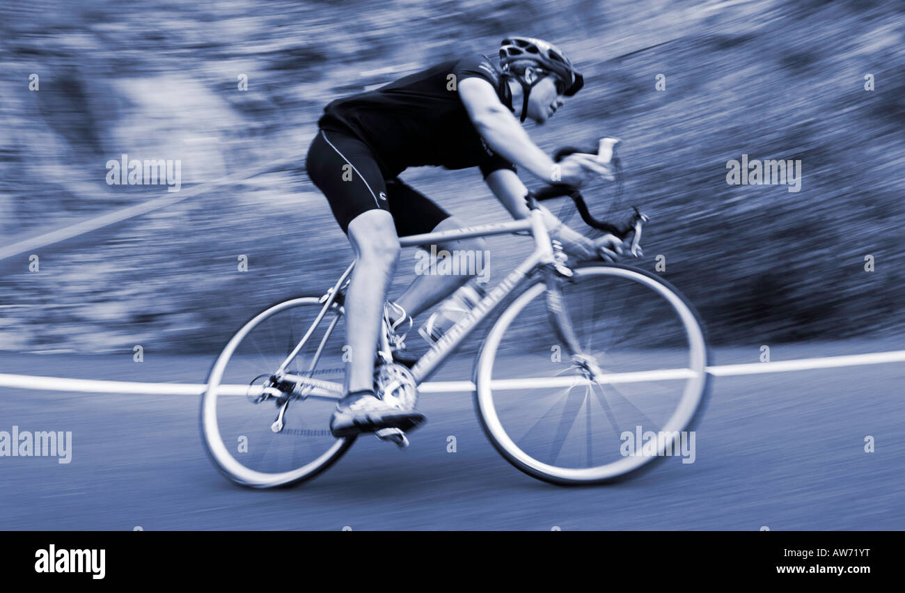 A road biker is taking a high speed turn on the winding mountain road ...