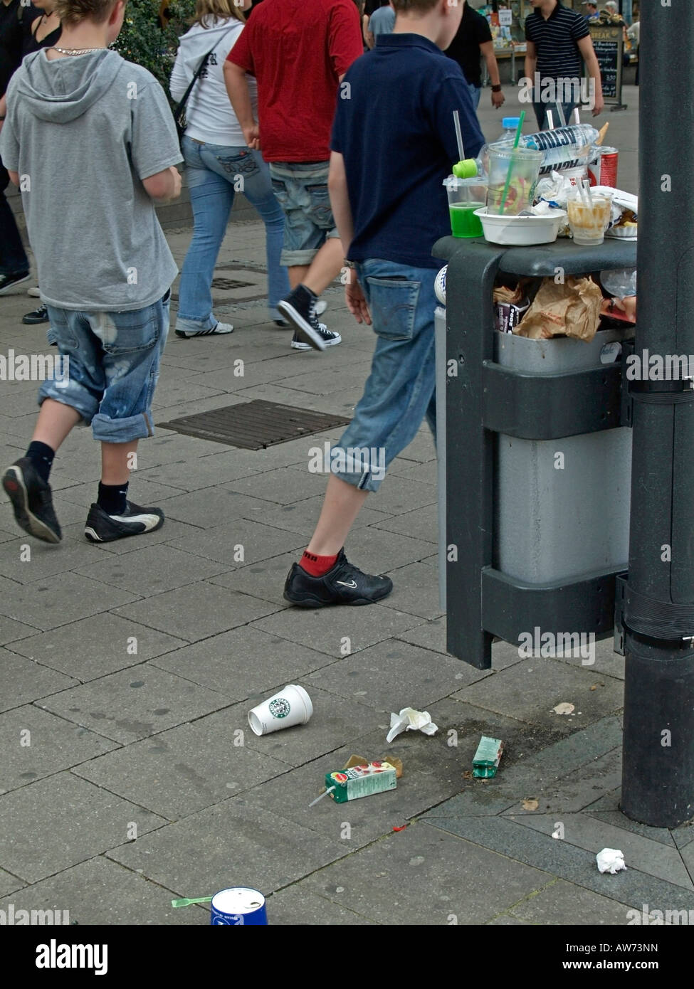 trash rubbish garbage and a full waste bin garbage can in pedestrian ...