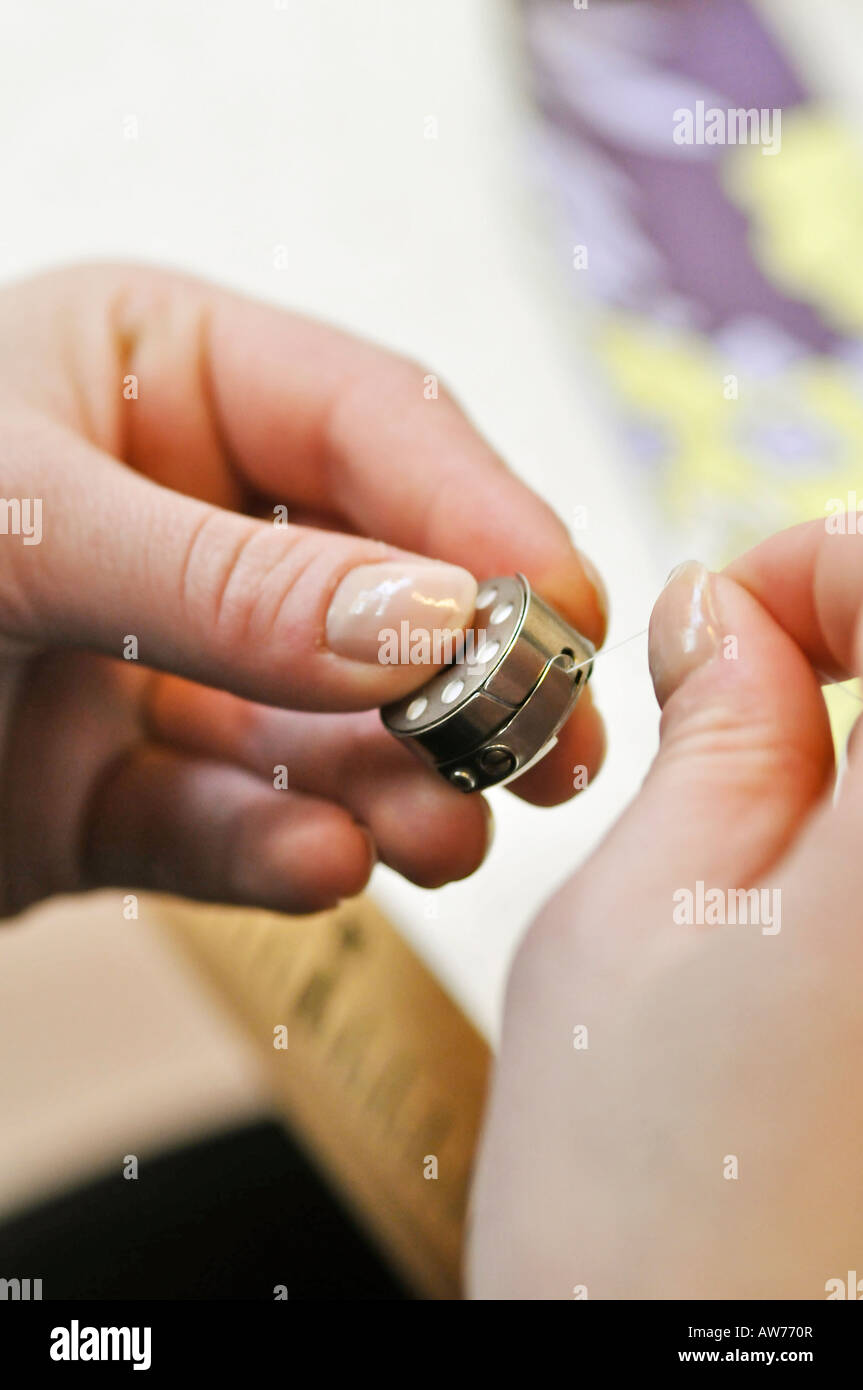 A dressmaker pulling the thread out of a spool Stock Photo - Alamy