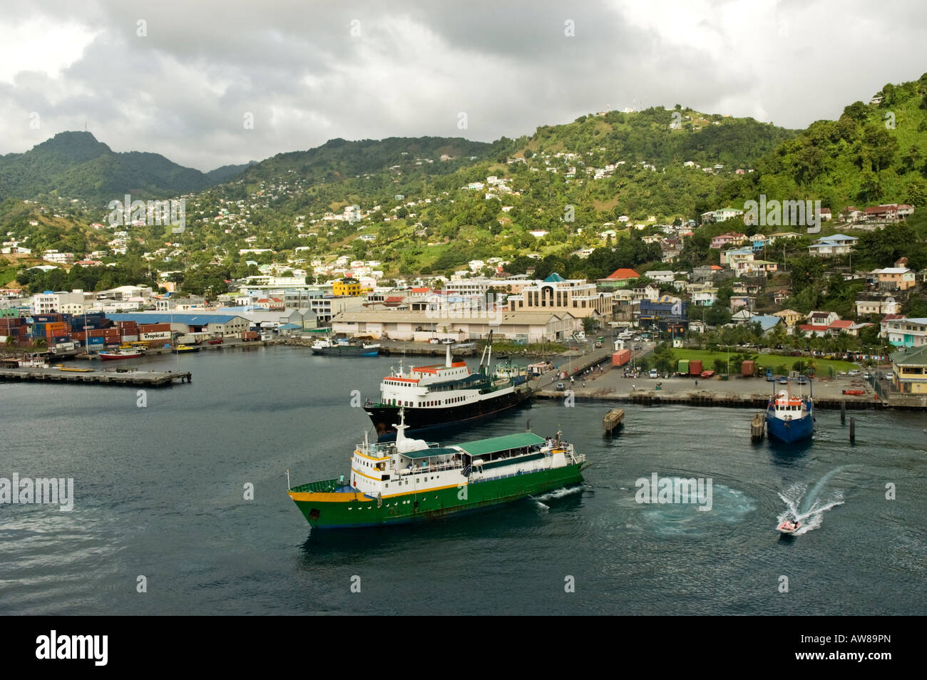 A small green and white Ferry leaving Kingstown Port where other ships ...