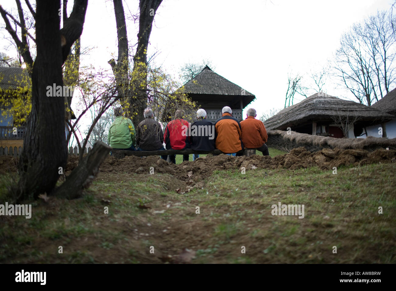 people wearing colored clothes sitting in front of a wooden cottage ...