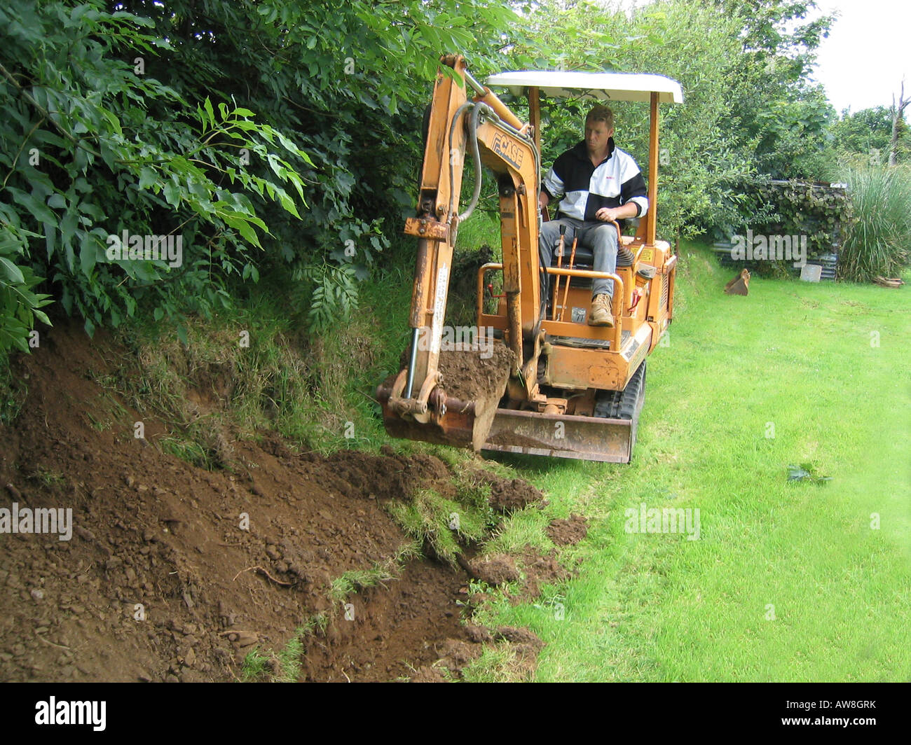 Digger small Caterpilar digging trench in green field for planting ...