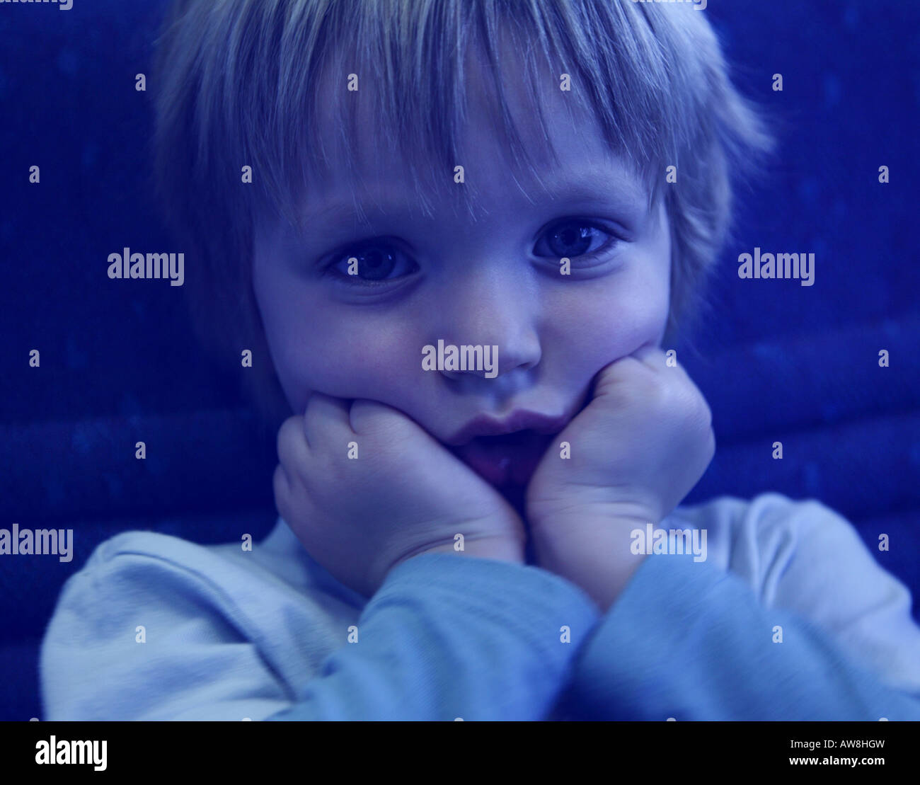 Young blond boy staring with hands on his face Stock Photo - Alamy