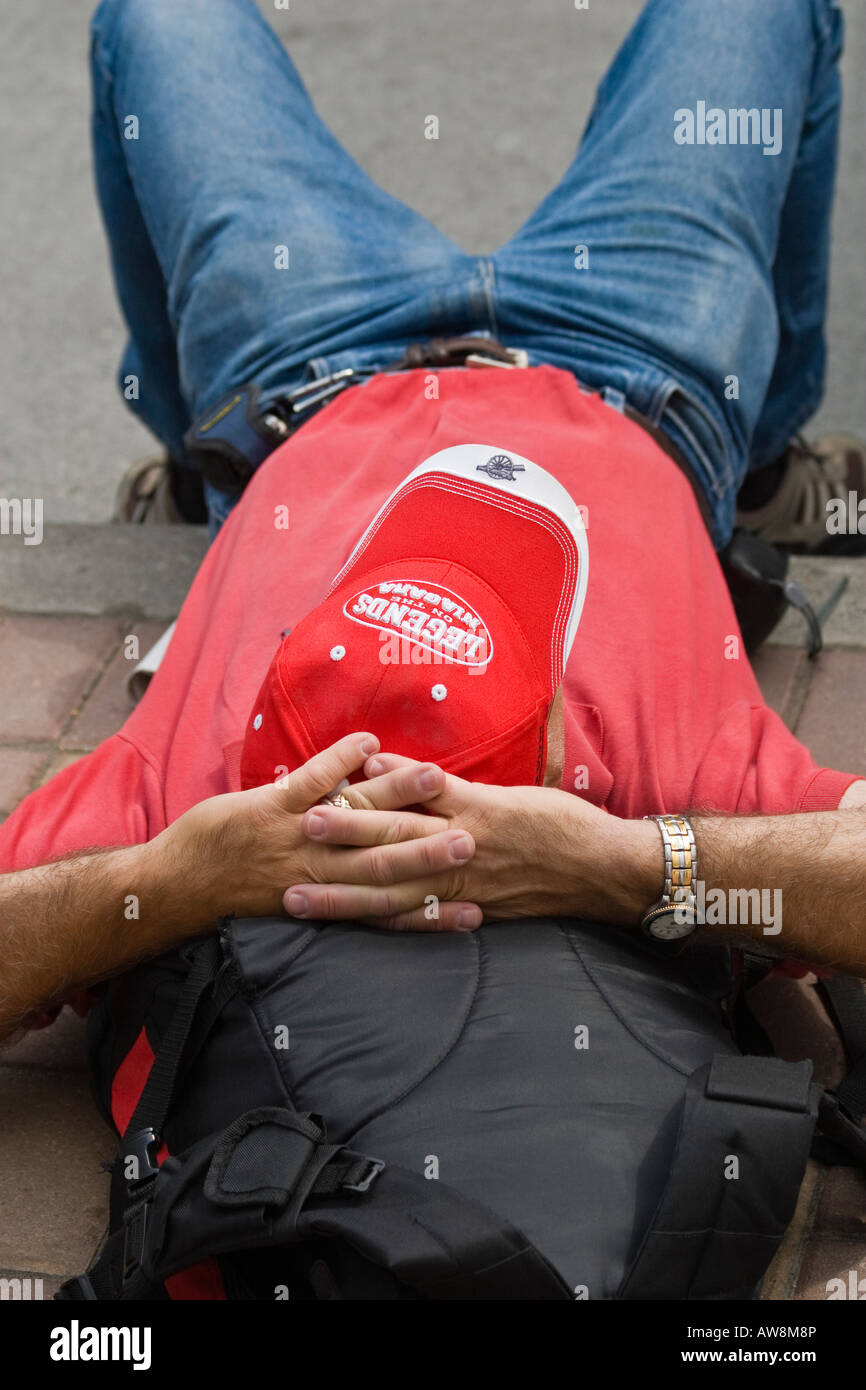 Neatly dressed man with backpack resting on curbside Stock Photo - Alamy