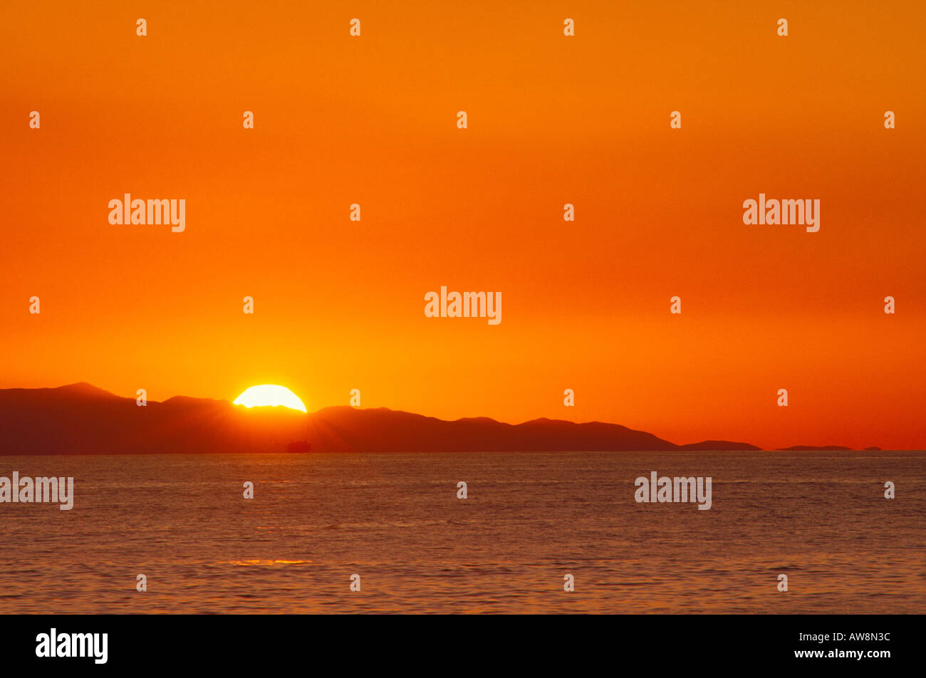 Sun setting behind Santa Cruz Island off shore oil platform visible ...