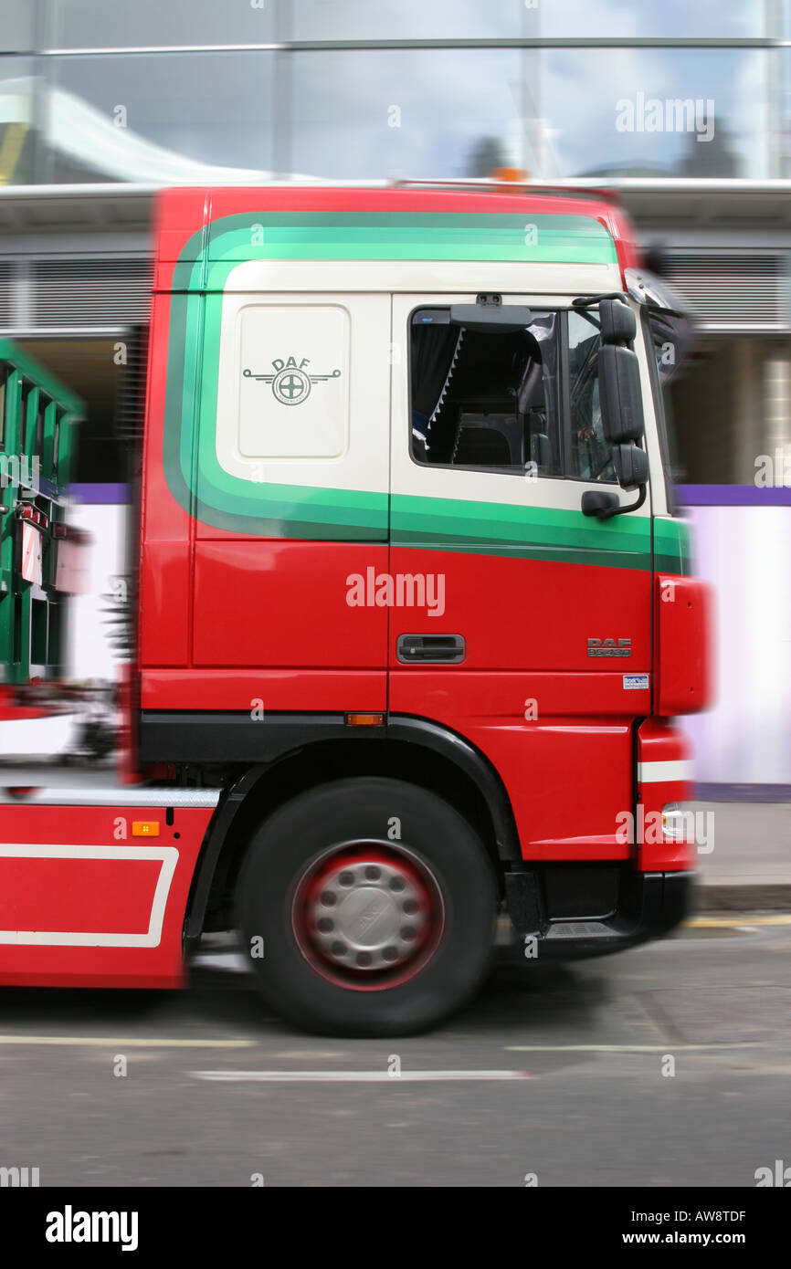 Red and white Daf truck side view with slight motion blur against glass ...