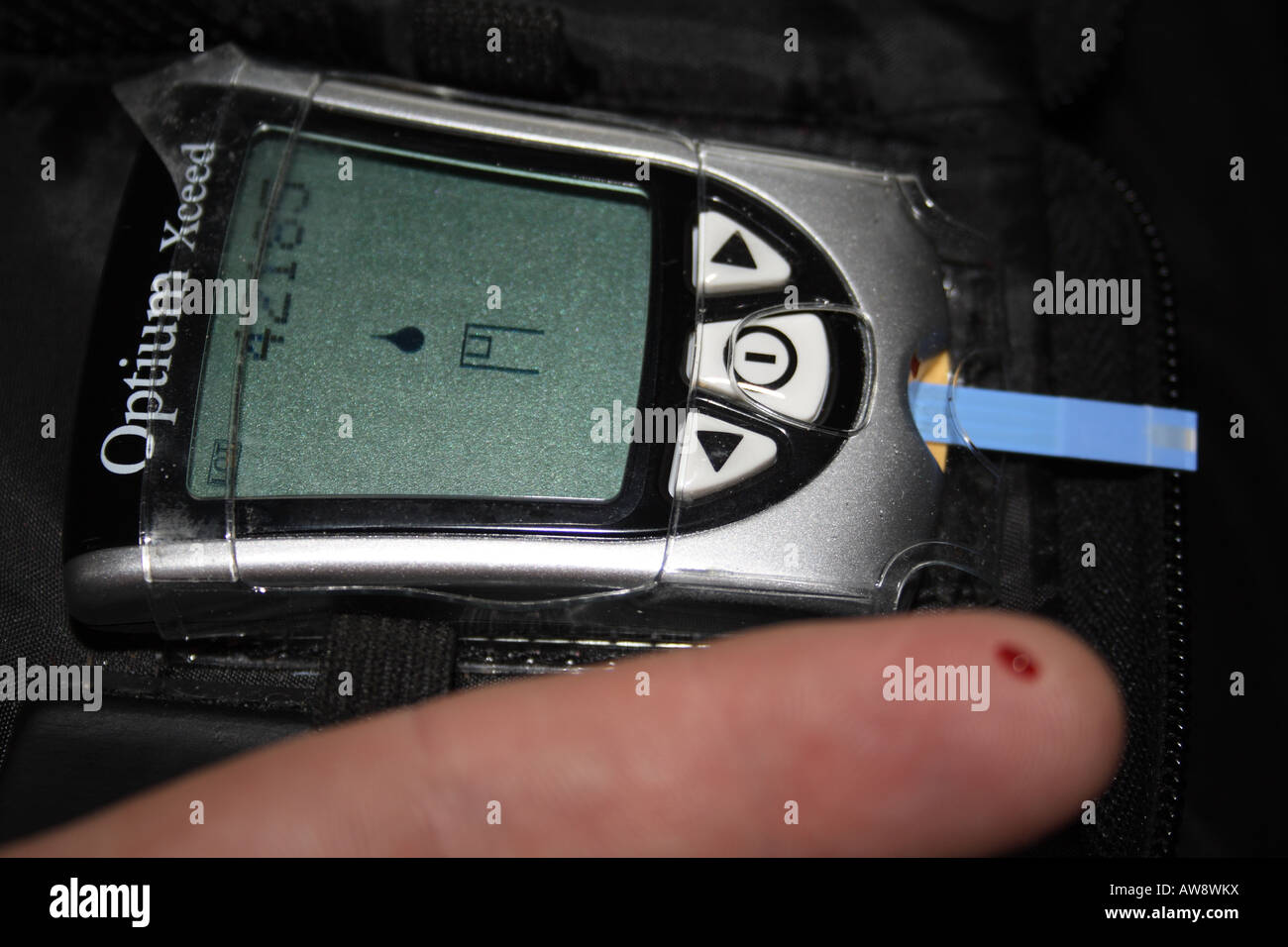 Diabetic blood sugar meter and pin prick of blood on index finger Stock ...